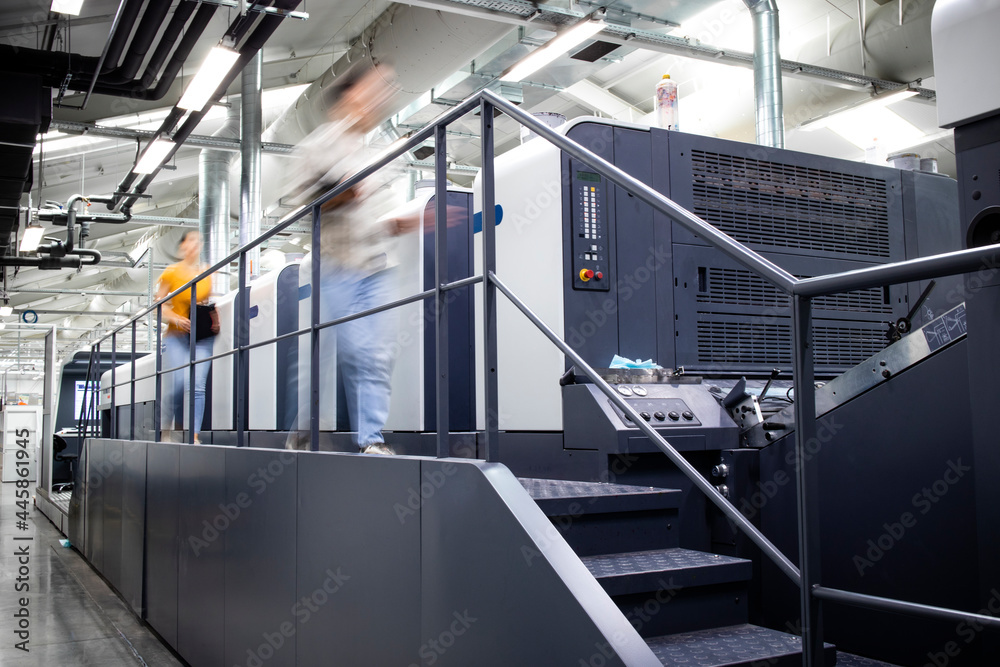 Printing factory interior with modern offset printing machine and busy ...