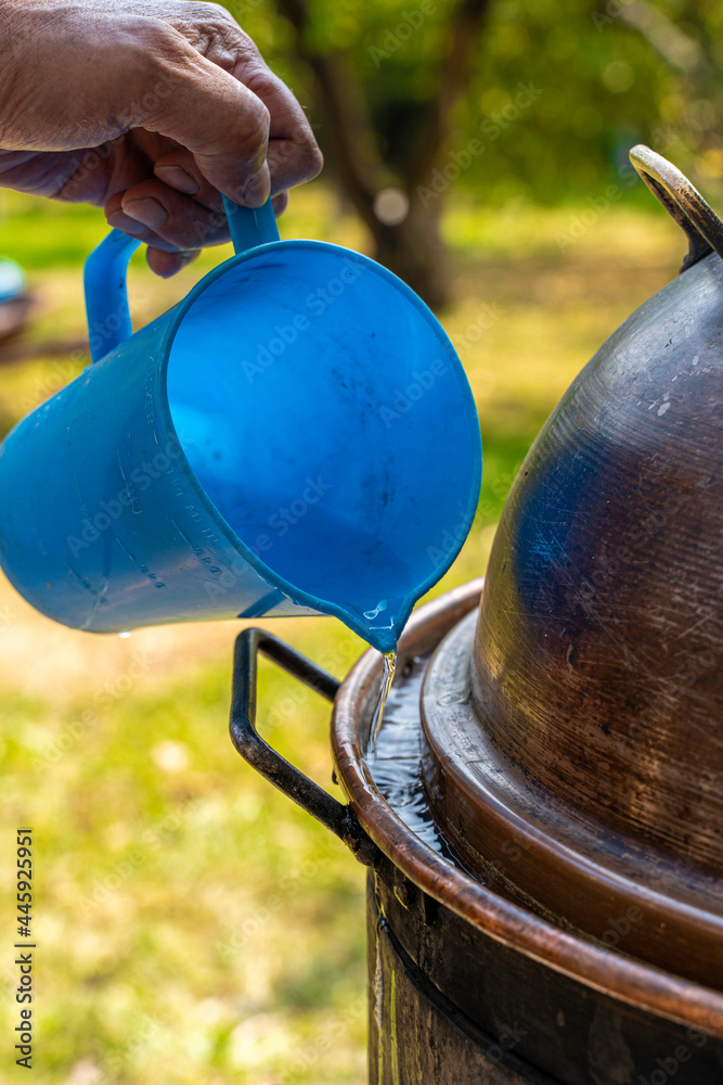 Cauldron for rakija brandy. Pouring water into the edges of the ...