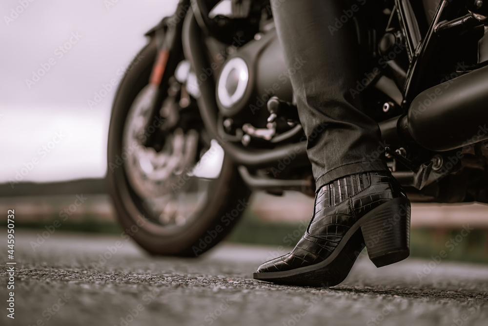 Legs of stylish motorcyclist woman sitting on classic bike. Black retro ...