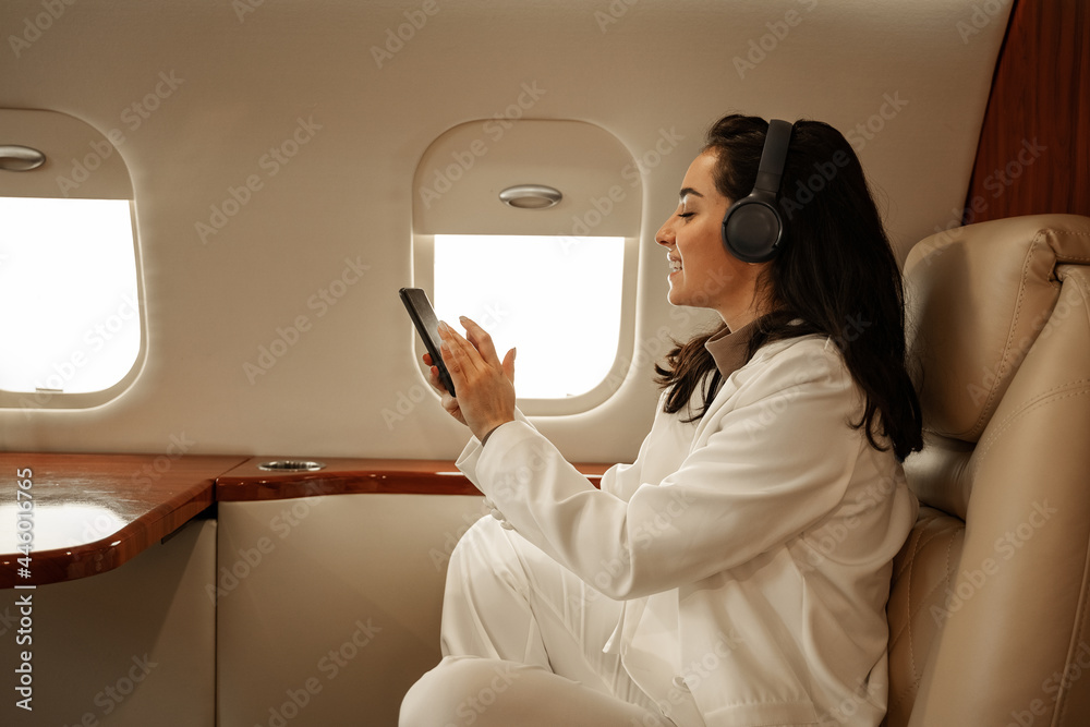 Beautiful girl, a passenger of the plane, having fun during the flight ...