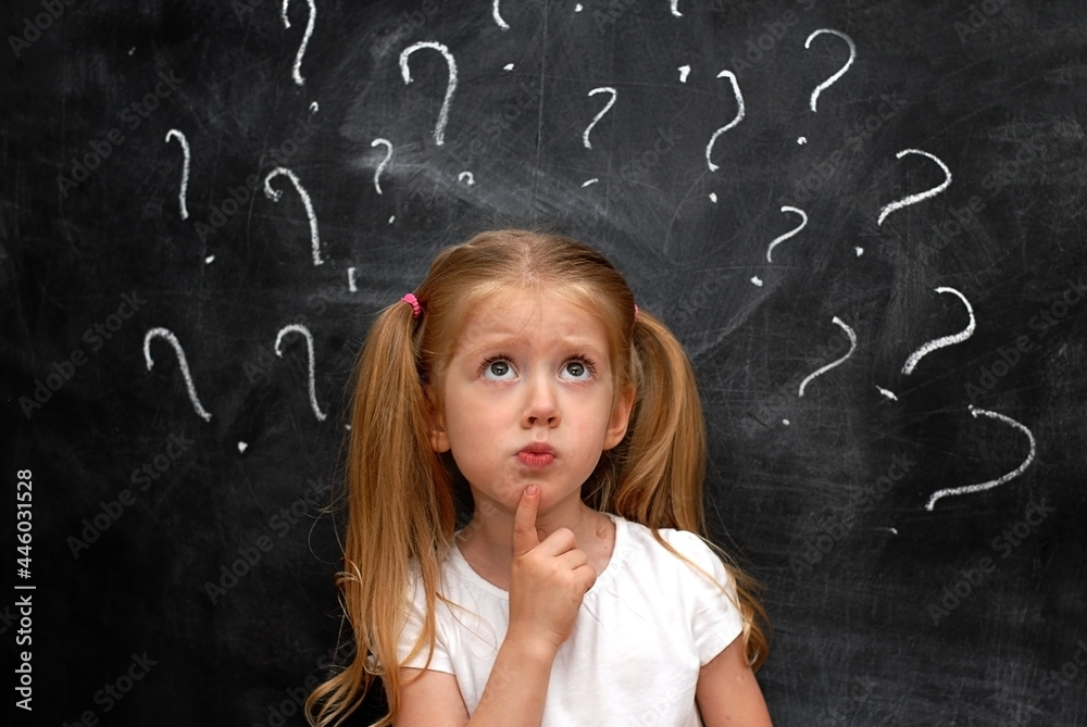 Blond schoolgirl girl on a black background of chalk board with a questioning expression on her ...