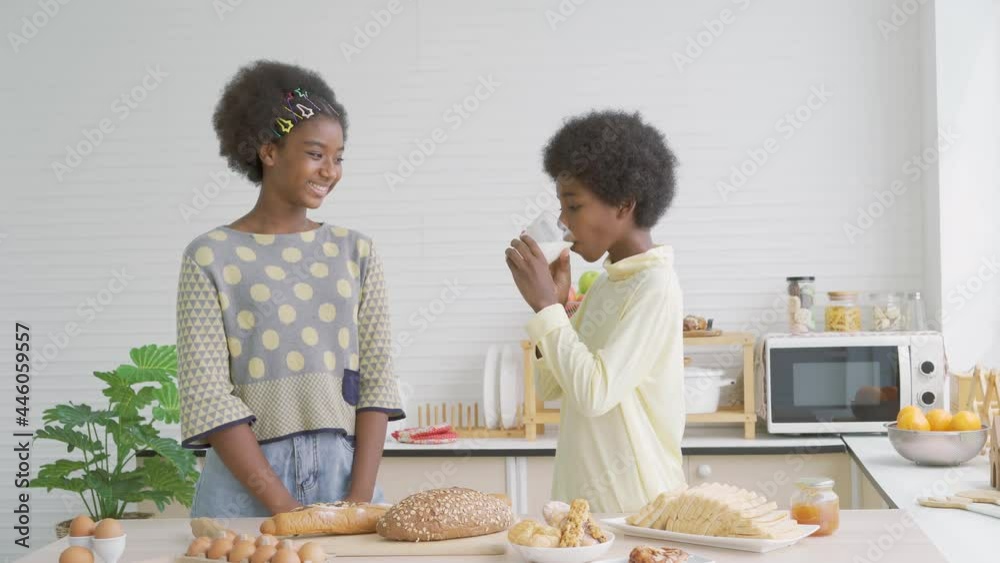 Cute little kids having breakfast with milk at kitchen, African american cute boy drinking milk ...