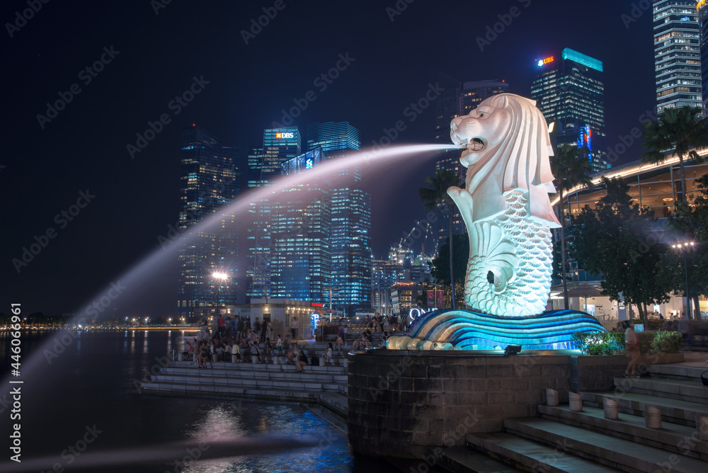 Merlion statue of Singapore at night, business buildings in the ...