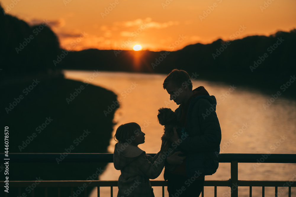 older brother and younger sister stand on the bridge ha sunset ...