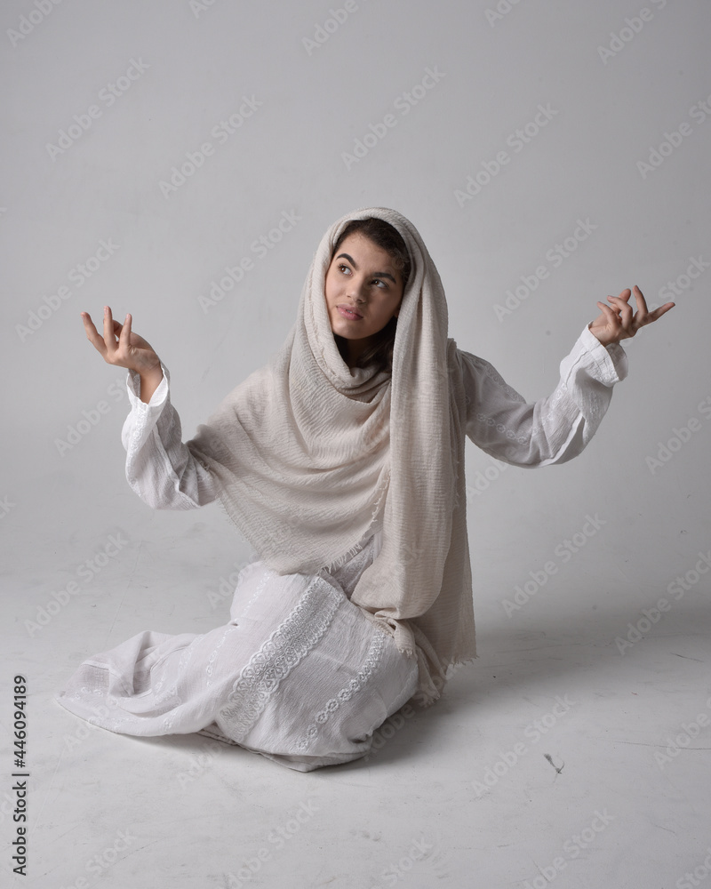 Full length portrait of young woman wearing classical white gown and a ...