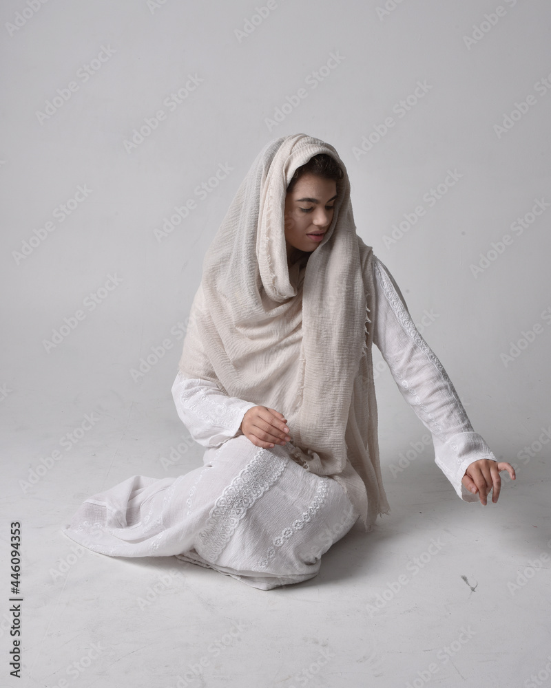 Full length portrait of young woman wearing classical white gown and a ...