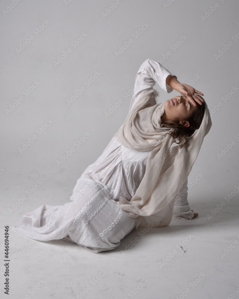 Full length portrait of young woman wearing classical white gown and a ...
