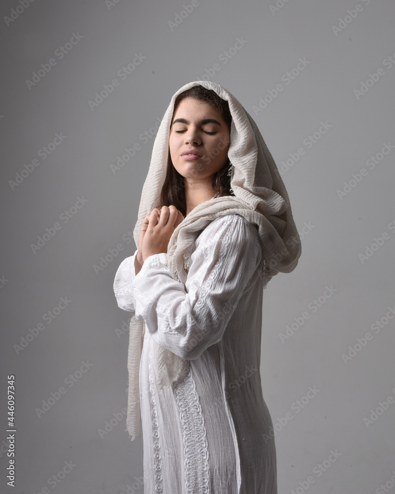 Full length portrait of young woman wearing classical white gown and a ...