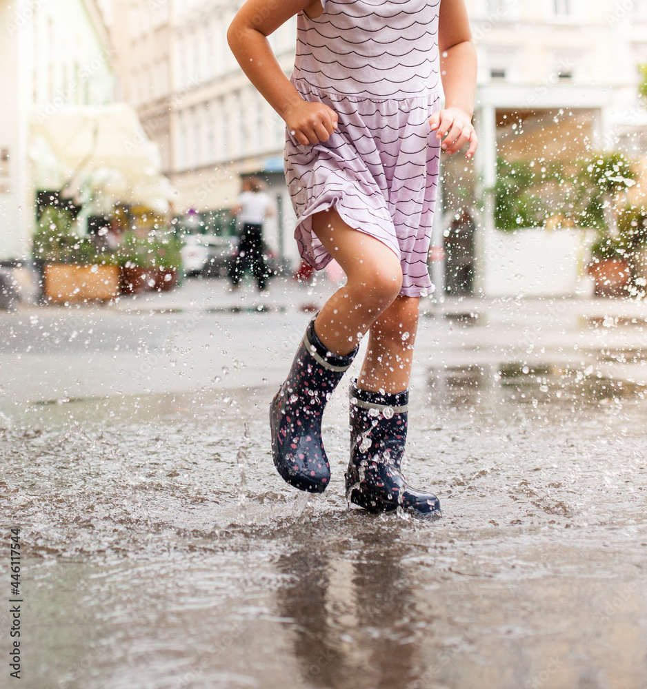 Child in rubber boots in puddle on hot summer day in the city. Kind in ...