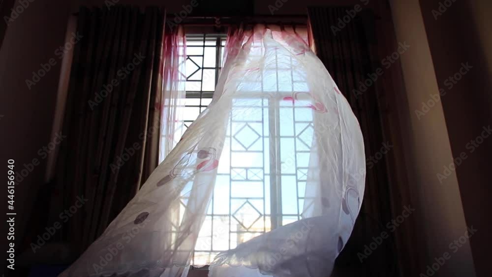 Wind coming through colourful curtain and iron window grilles from blue ...