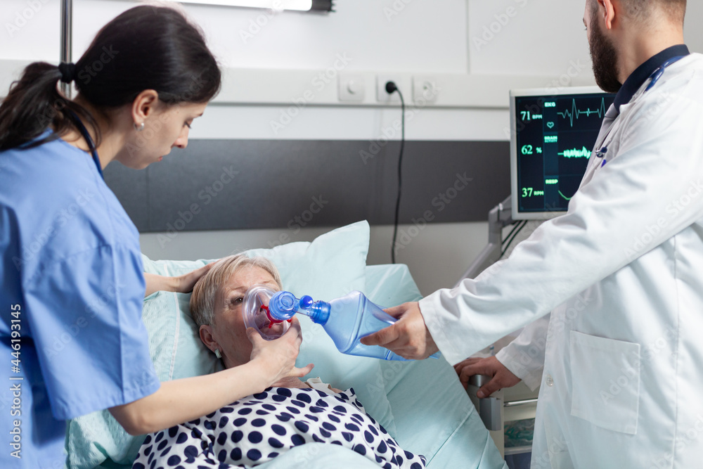 Medical team helping senior woman patient laying in hospital bed, to ...