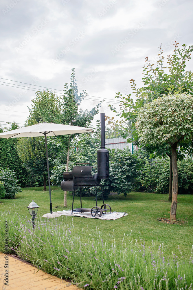 Smoker grill in home backyard, container with coal, smoke coming out of ...