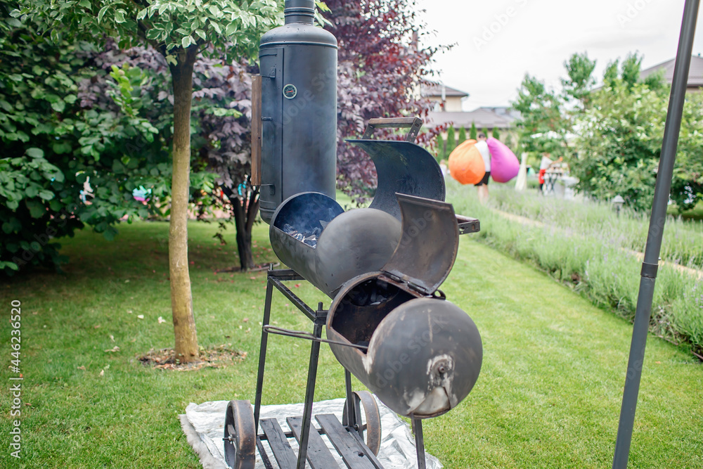 Smoker grill in home backyard, container with coal, smoke coming out of ...