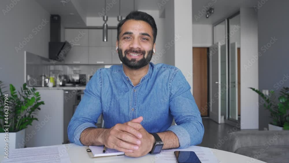 Confident smiling indian man in earphones making video conference call ...
