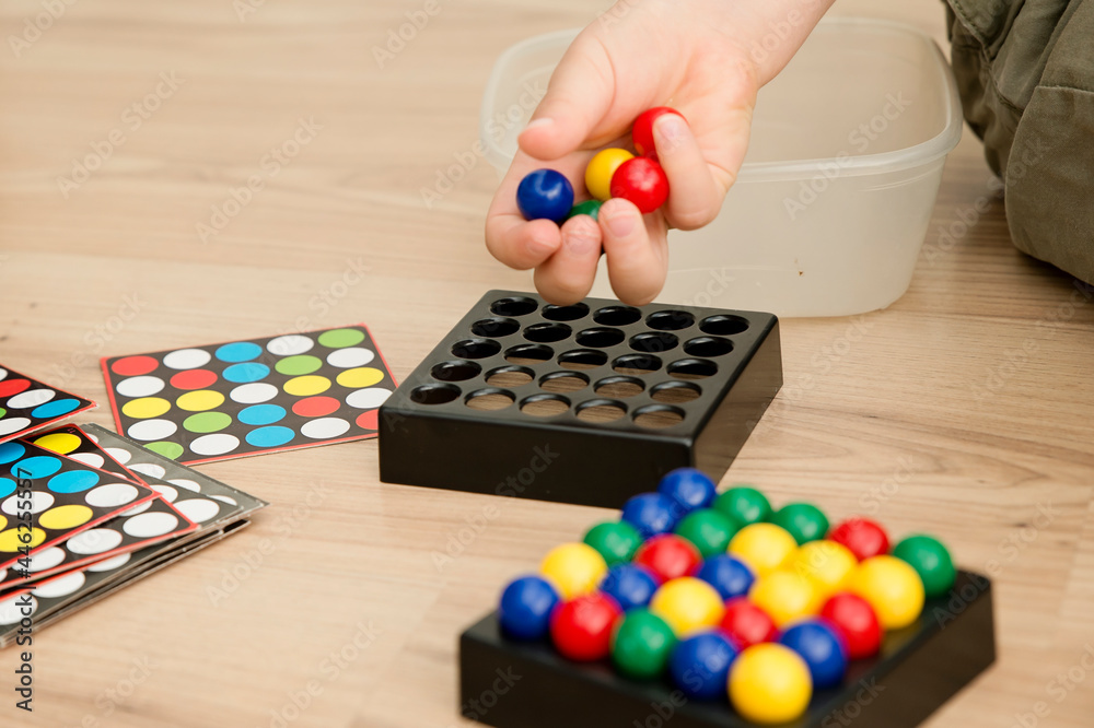 Childs hand on colorful wooden marbles. Color sequence logic game. A ...