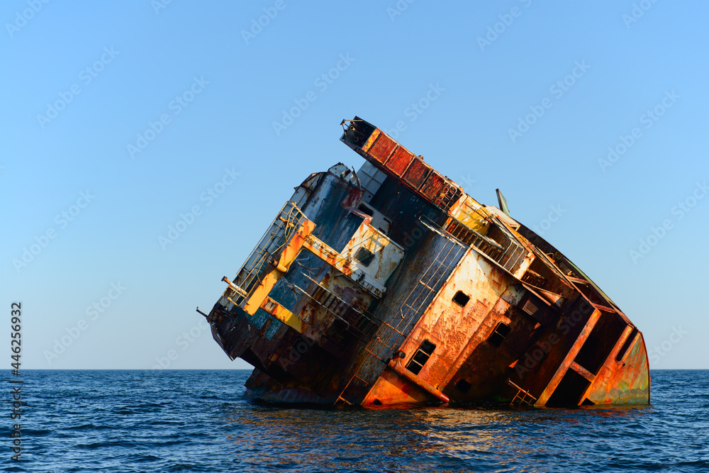 The rusting remains of the hull of a stranded ship in the open sea ...