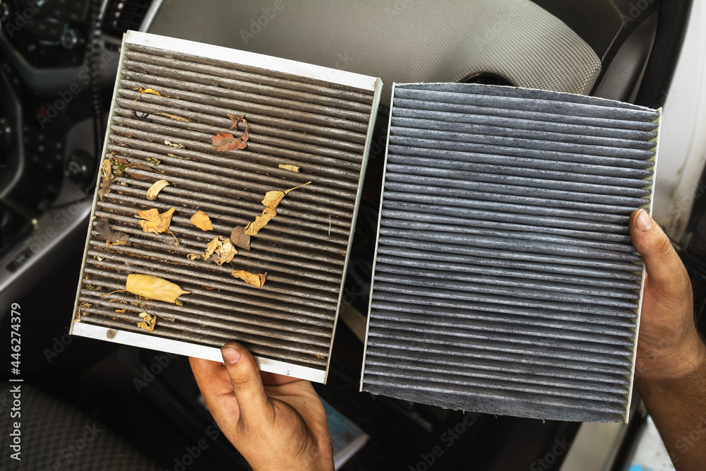 An auto mechanic shows a close-up of an old and new cabin air filter ...
