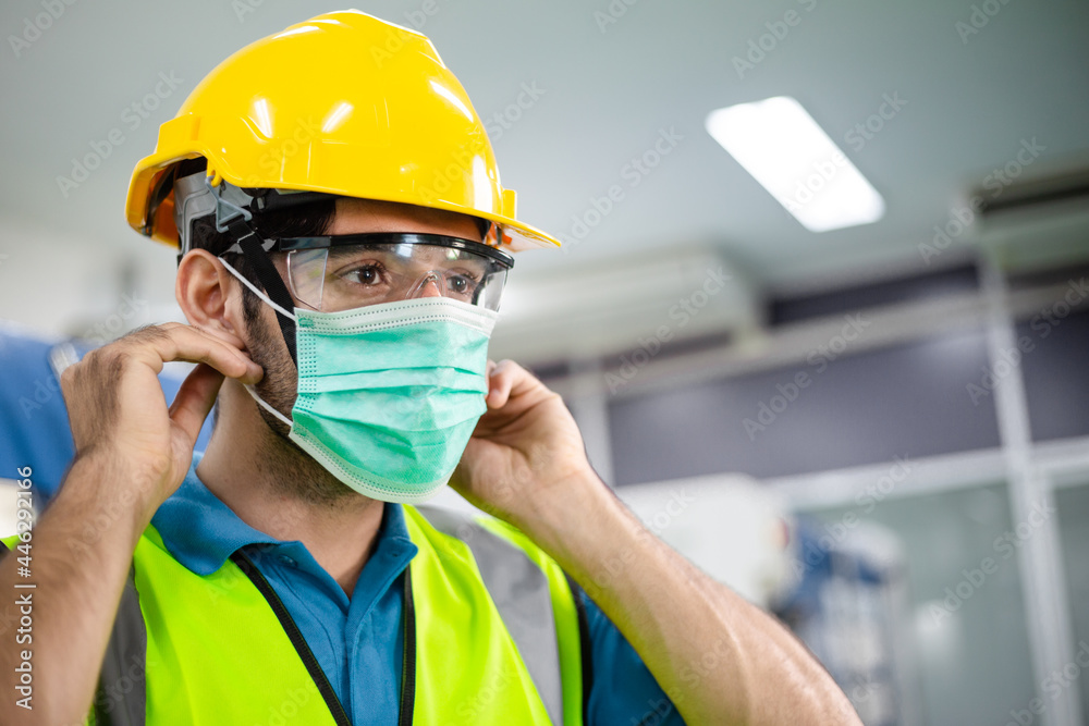 Male engineer worker wearing protective face mask, safety helmet and ...