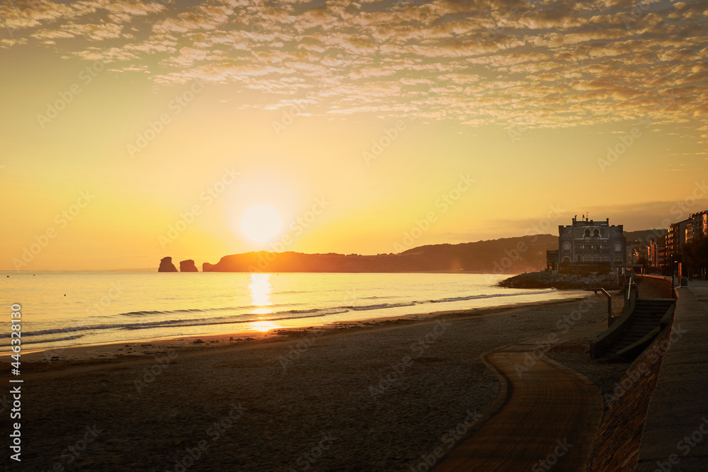 sunrise on the beach, a close-up of the sand and in the background two ...