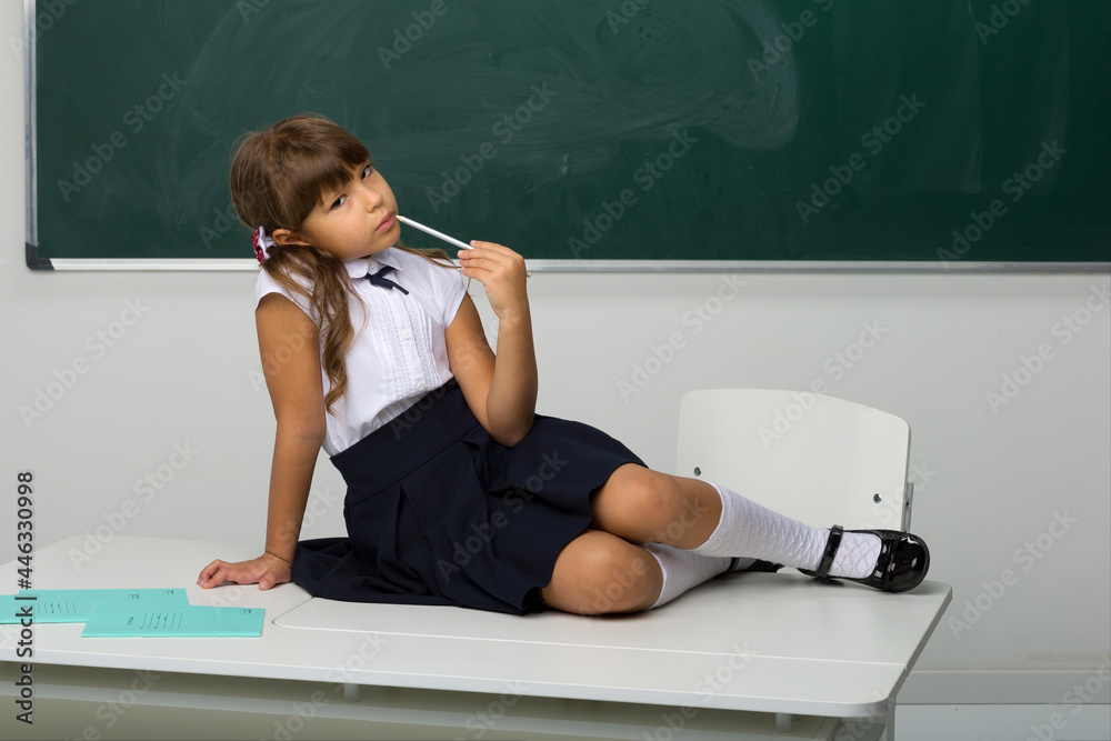 Cute girl sitting on desk in classroom Stock Photo | Adobe Stock