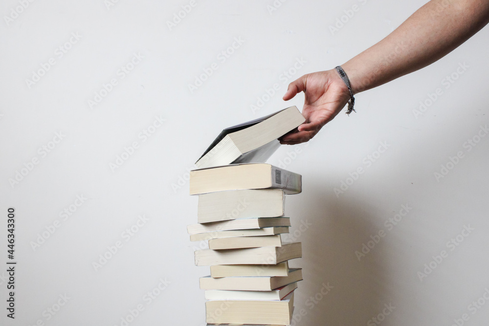 hand grabbing stacked books Stock Photo | Adobe Stock