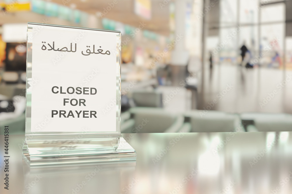 CLOSED FOR PRAYER table sign in Arabic and English in front of a half ...