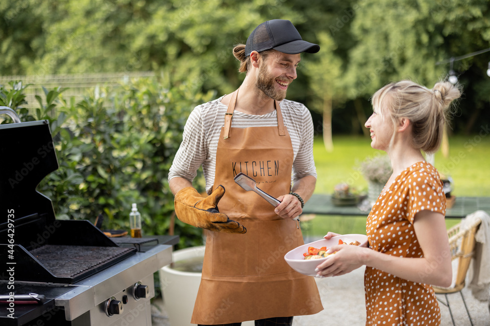 Young couple have fun while cooking vegetables on grill at backyard on ...