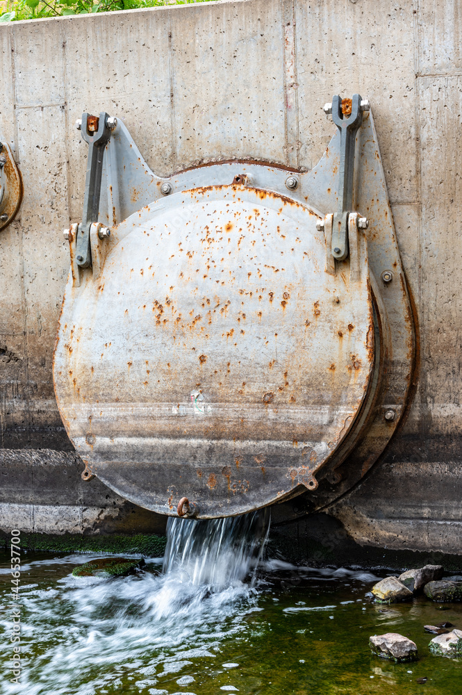 Heavy metal flood control gate discharging into a waterbody Stock Photo ...