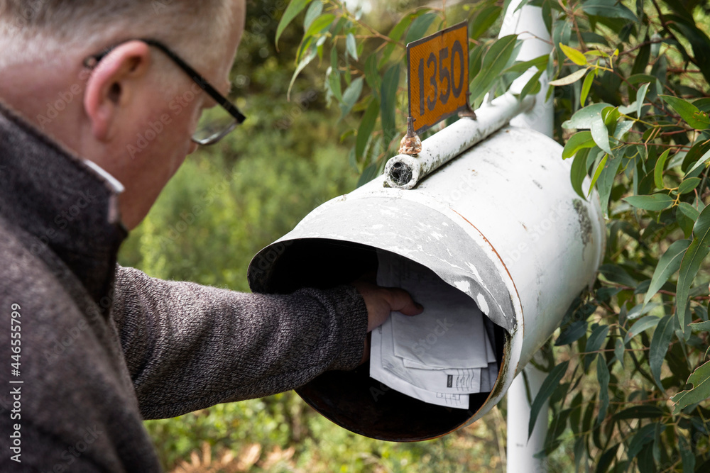 Senior man collecting mail from shared mailbox. Stock Photo | Adobe Stock