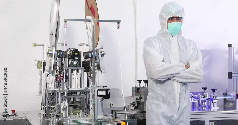 Male worker in sterile cloths working in face mask production line ...