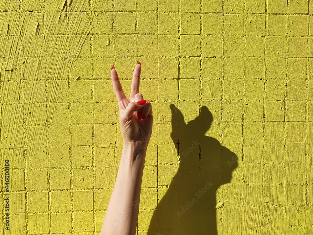 Peace sign hand. Woman's hand makes two fingers up gesture on neon ...