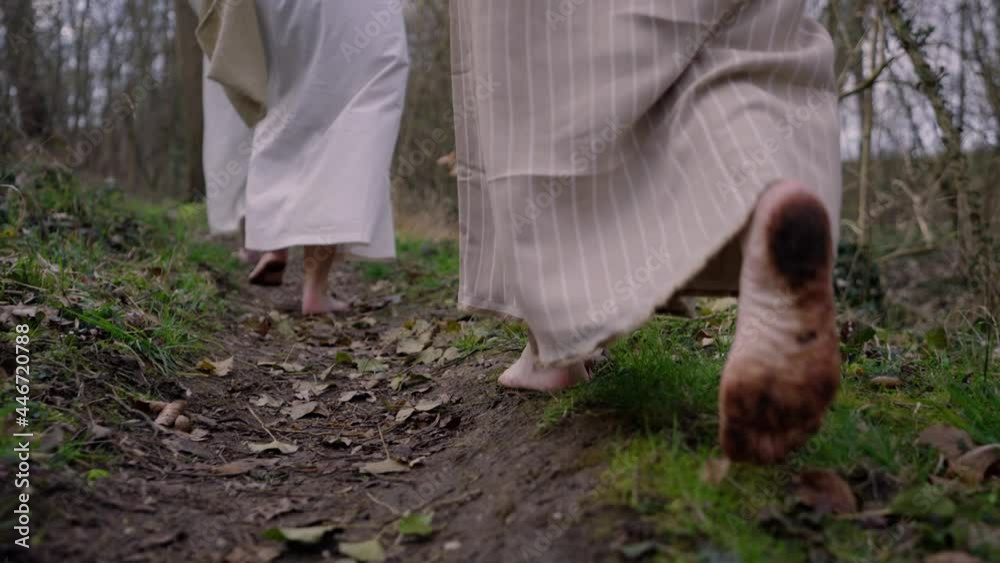 Three ancient women in traditional clothing walk barefoot through the ...