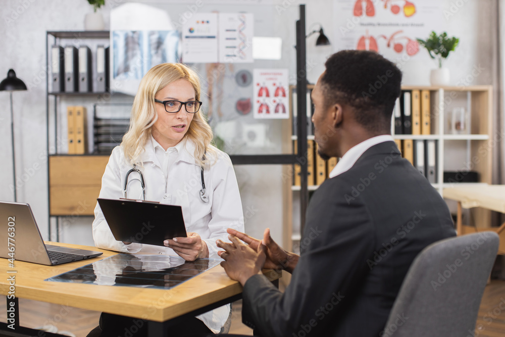 Caucasian female doctor in lab coat and eyeglasses talking with male ...
