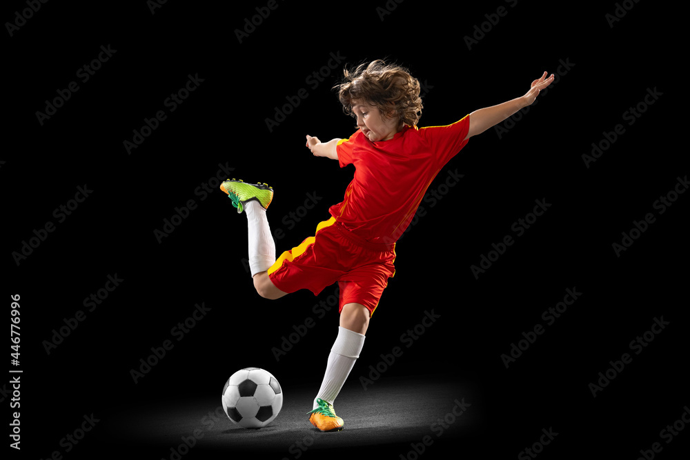 In motion. One little male football soccer player, boy training with ...