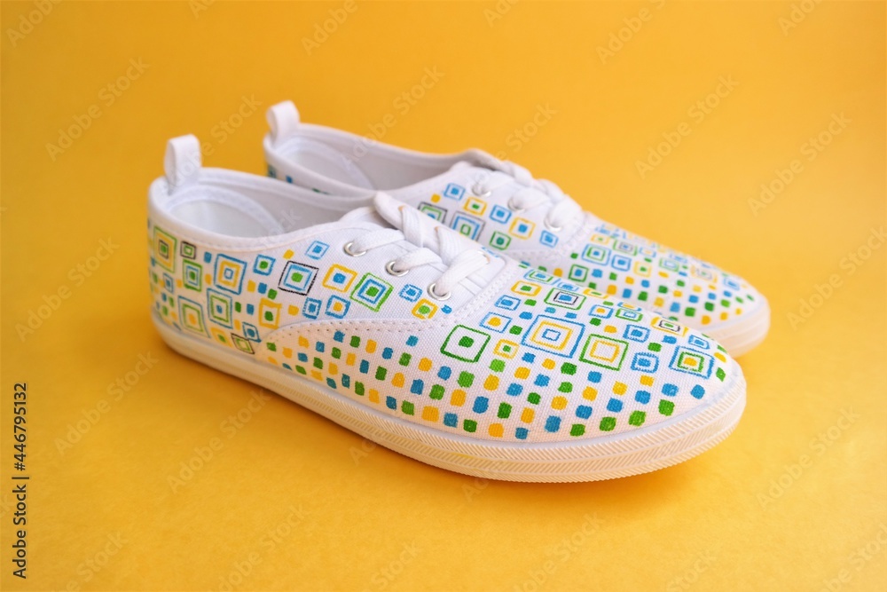 white sneakers with hand-painted geometric shapes on a yellow ...