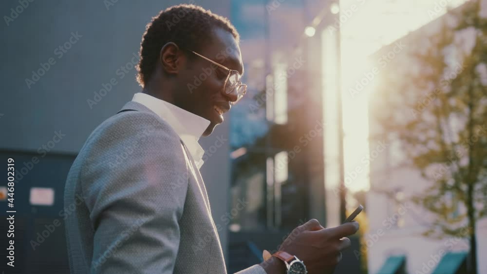 On street african american young man with glasses using phone stand on ...