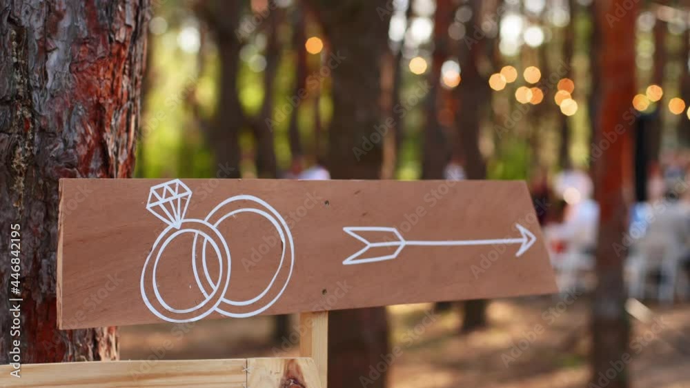 Wooden arrow sign with wedding rings on ceremony venue. Wedding party ...