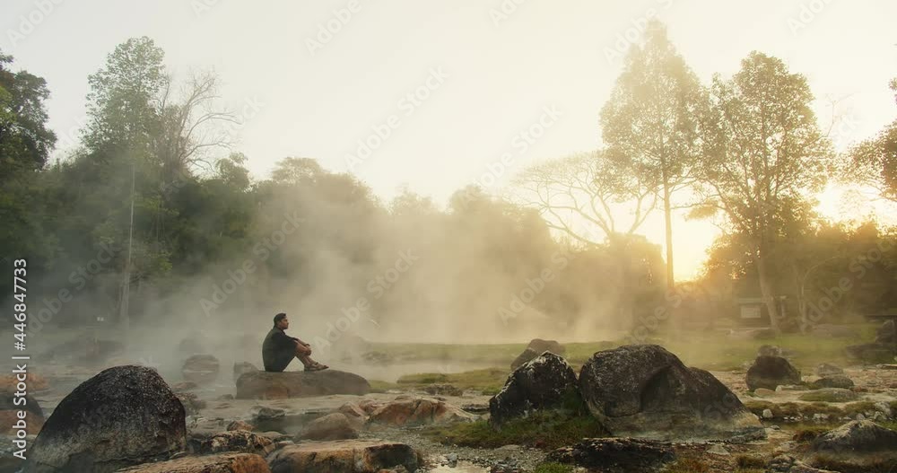 Young tourist traveler man sitting relaxing on the rock and looking at ...