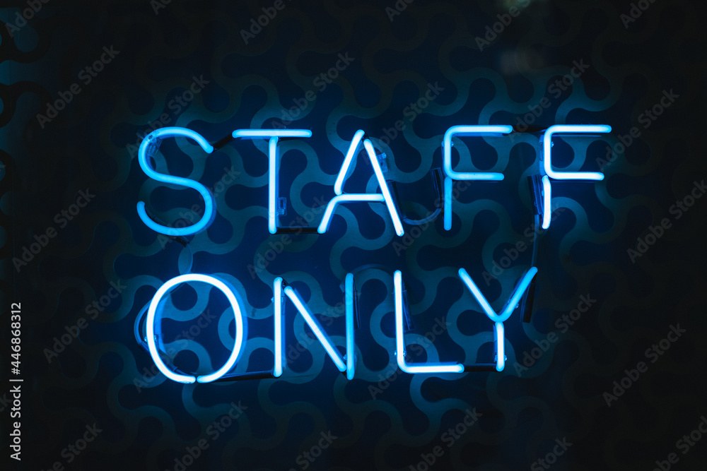 Neon letters, bright signboard staff only on a black wall close-up ...