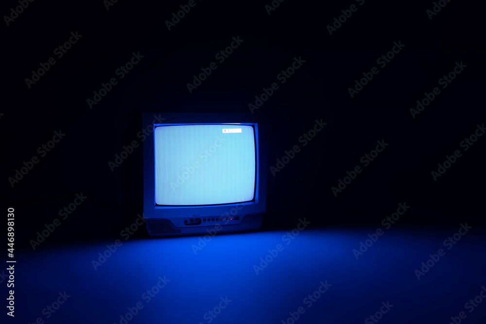In the dark, there is a working blue screen old CRT TV that gives a ...