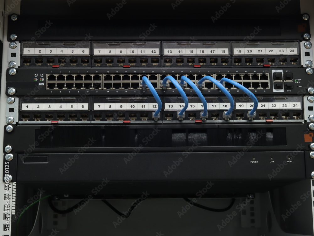 An Ethernet switch and patch panels installed in a low-current rack. Stock Photo | Adobe Stock