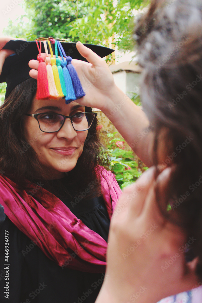 smiling portrait of queer young woman with university graduation cap ...