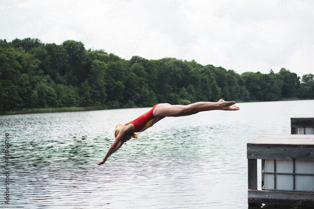 Athletic woman in red swimsuit diving into lake in Poland Stock Photo ...