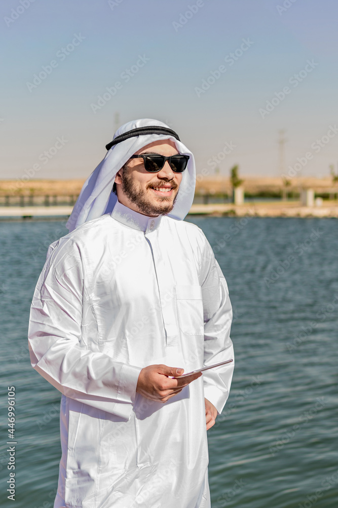 Happy Muslim man in traditional clothing, smiling at maritime zone, in ...