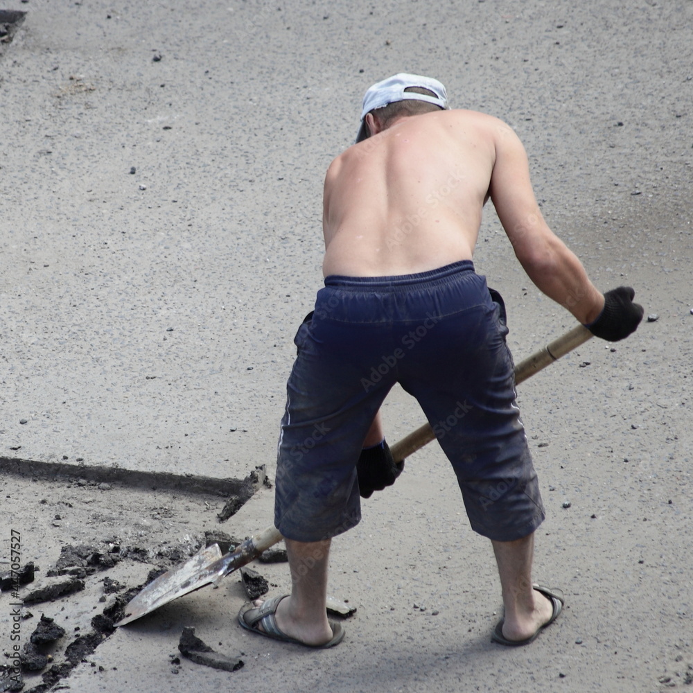 One Caucasian road worker without protective clothing removes old ...