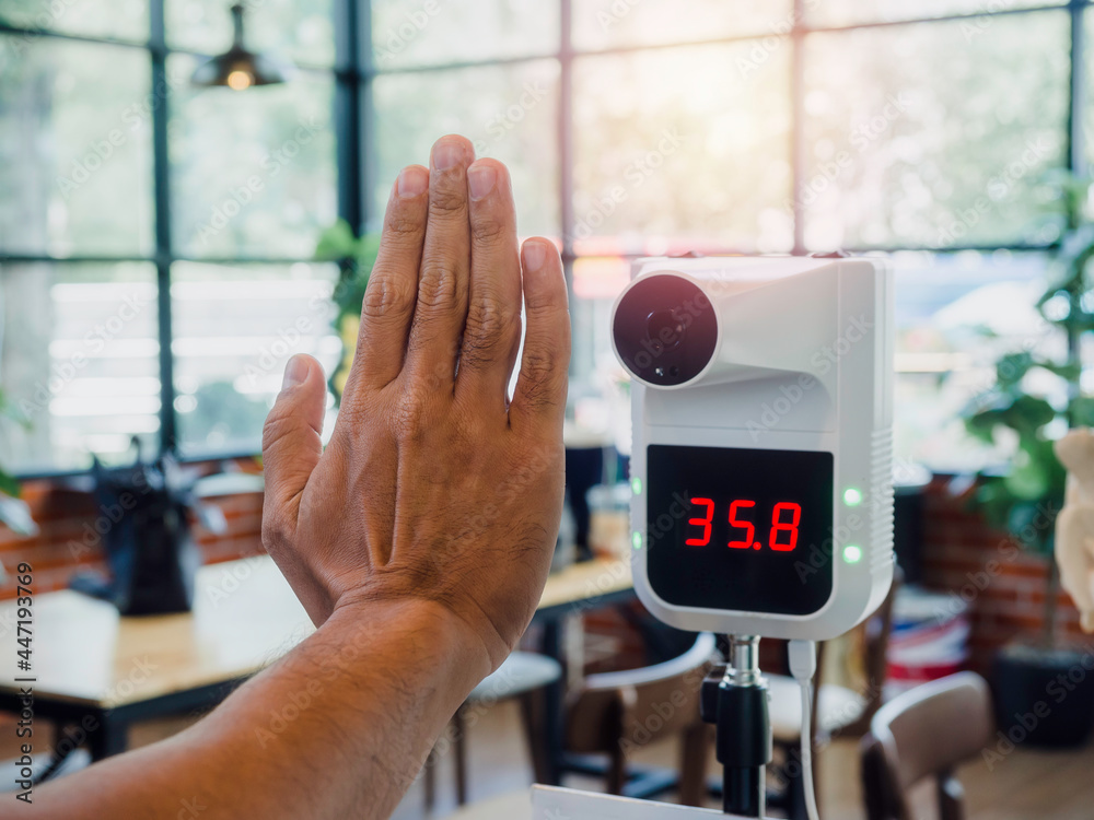 Man hand checking temperature before entering cafe with digital ...