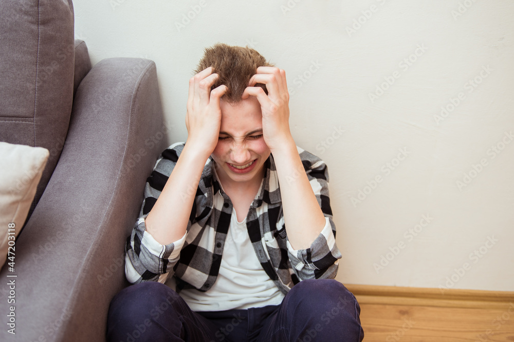 Tired teen boy feeling strong headache, migraine pain, holding head ...