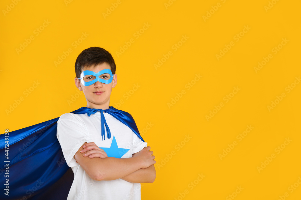 Teenage boy in superhero costume on yellow background. Space for text ...