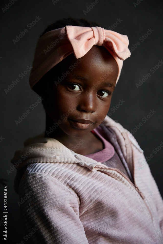 Low-key portrait of beautiful black South African girl wearing pink ...