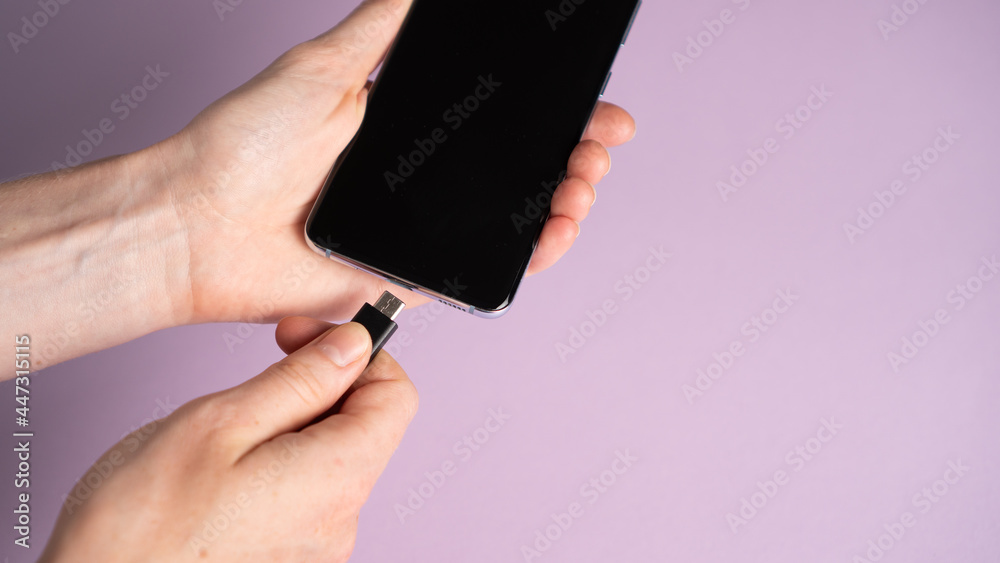 Phone in a hand. Charging smartphone. Plugin Type-C cord into the phone ...